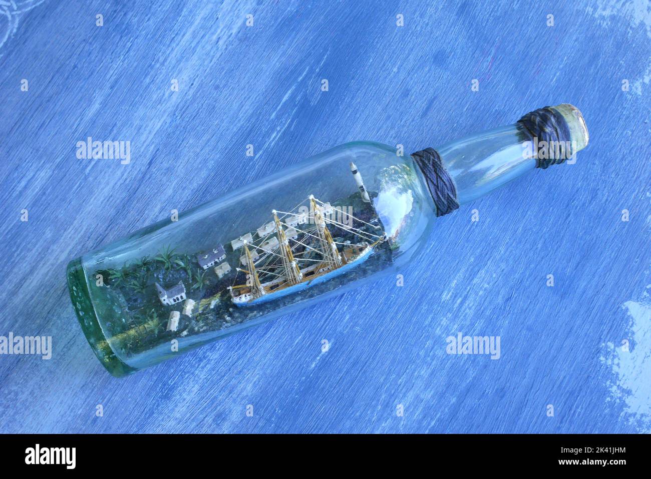 Fully rigged ship in a bottle on a blue background Stock Photo - Alamy