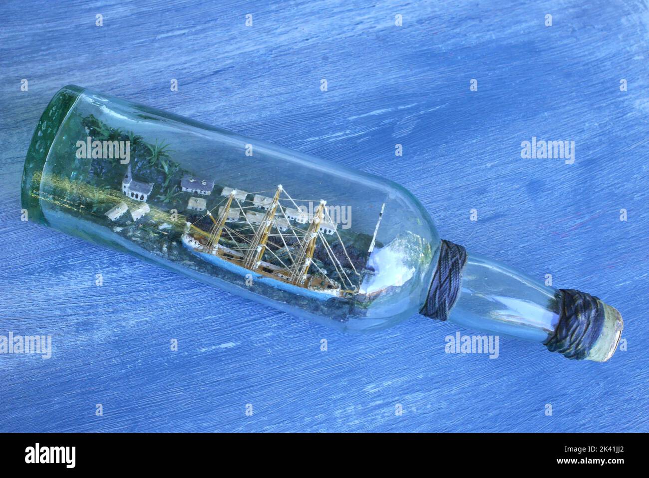 Fully rigged ship in a bottle on a blue background Stock Photo - Alamy