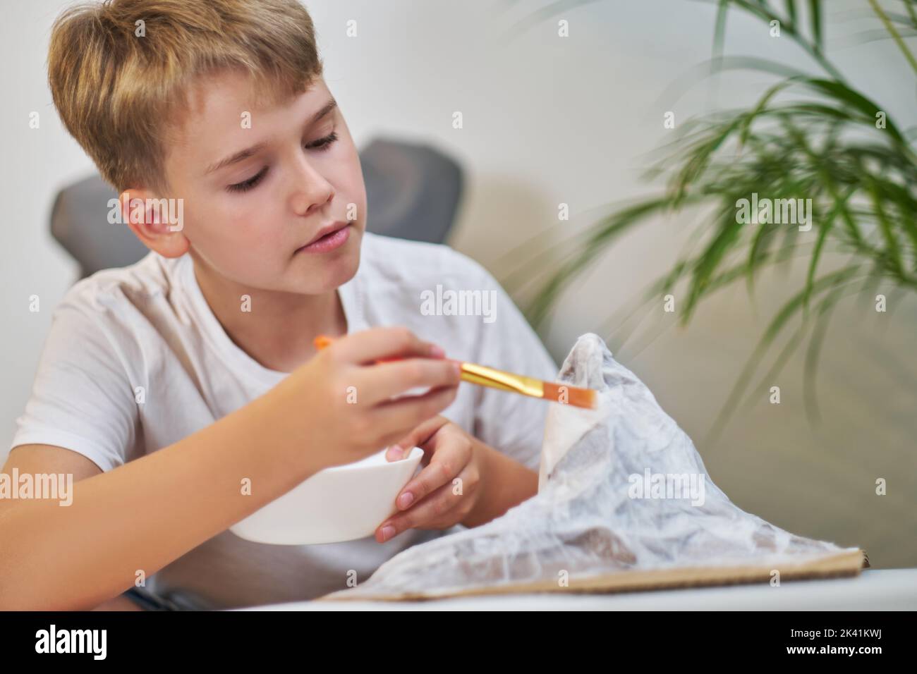 Schoolboy makes creative project in form of papier mache mountain Stock ...
