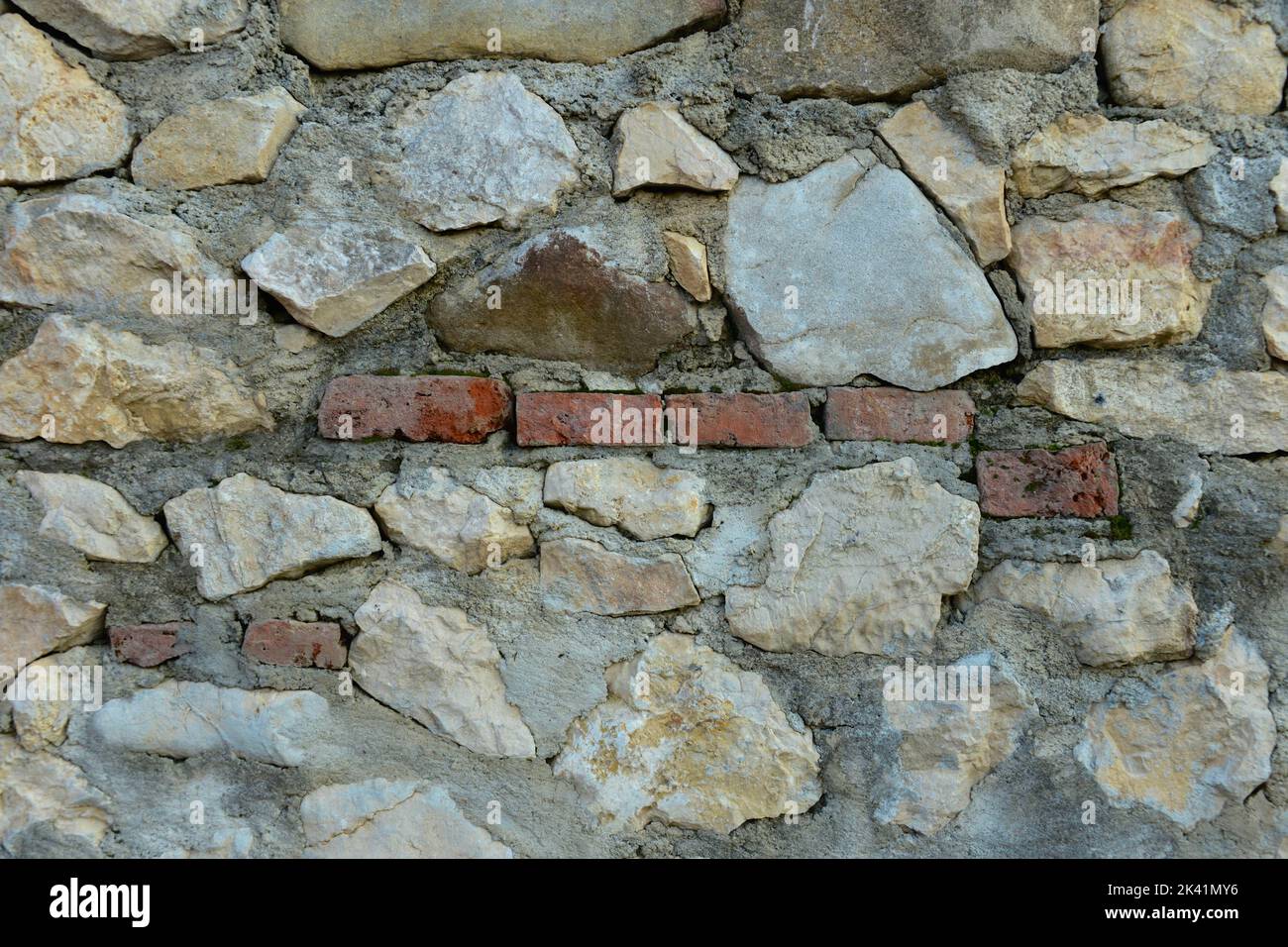 Natural stone wall with a brick stripe Stock Photo - Alamy