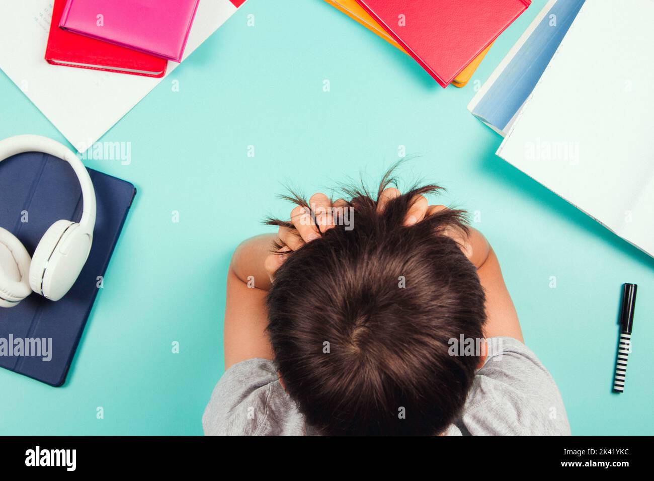 Sad tired frustrated teenage boy sitting at the table with many books ...