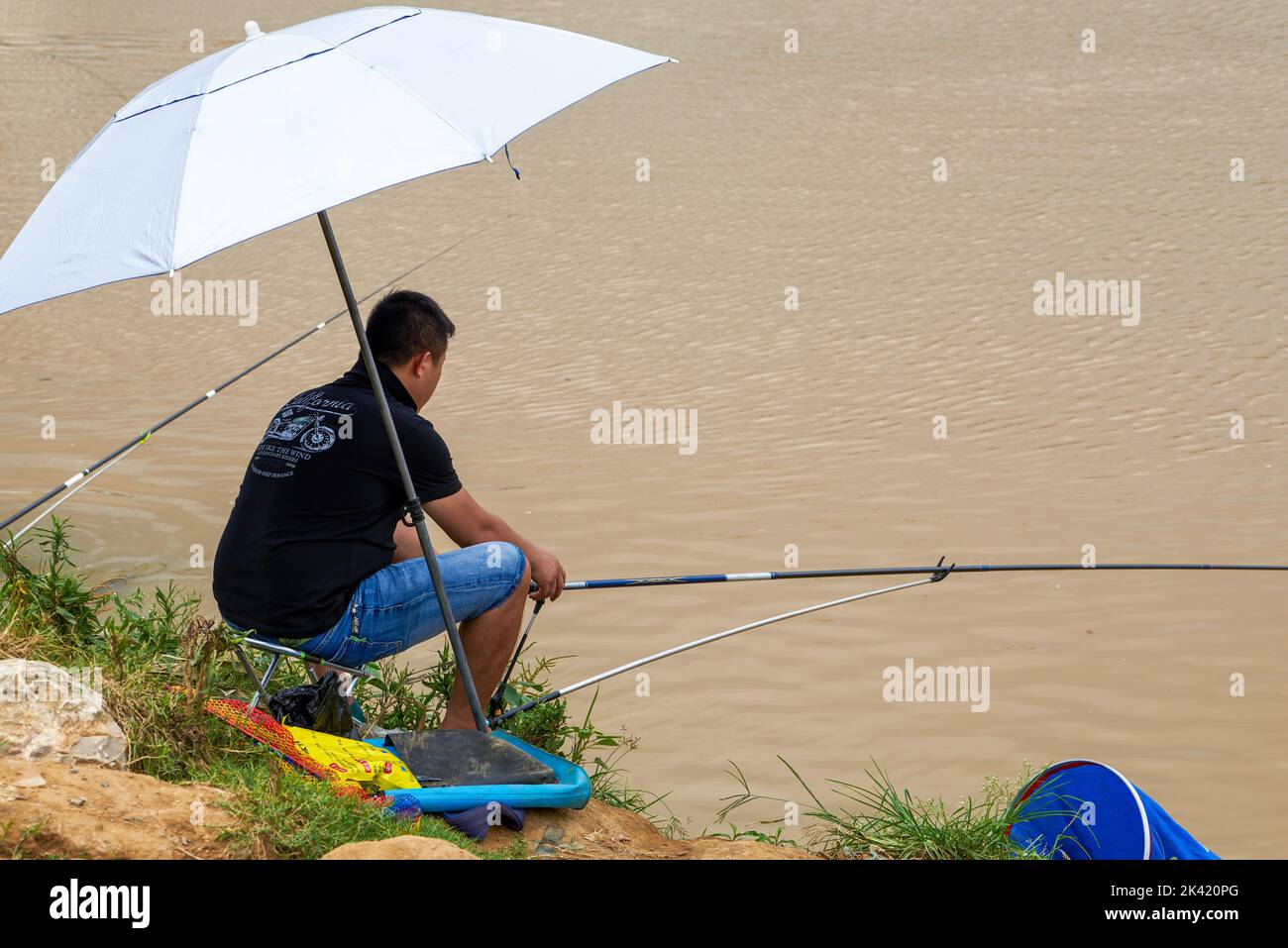 people fishing recreationally by the river Stock Photo - Alamy