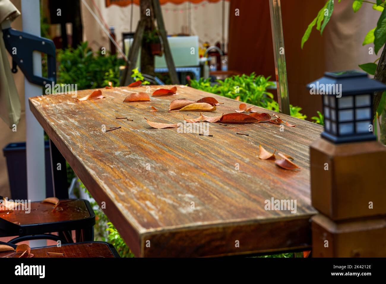 Wooden table with fallen leaves in outdoor garden Stock Photo - Alamy