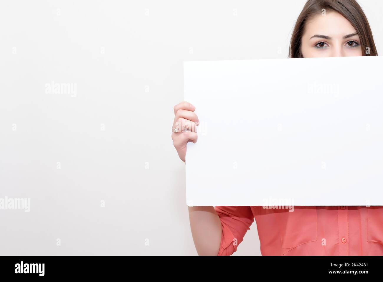 Young woman with an empty sheet of paper half covering face stock photo ...