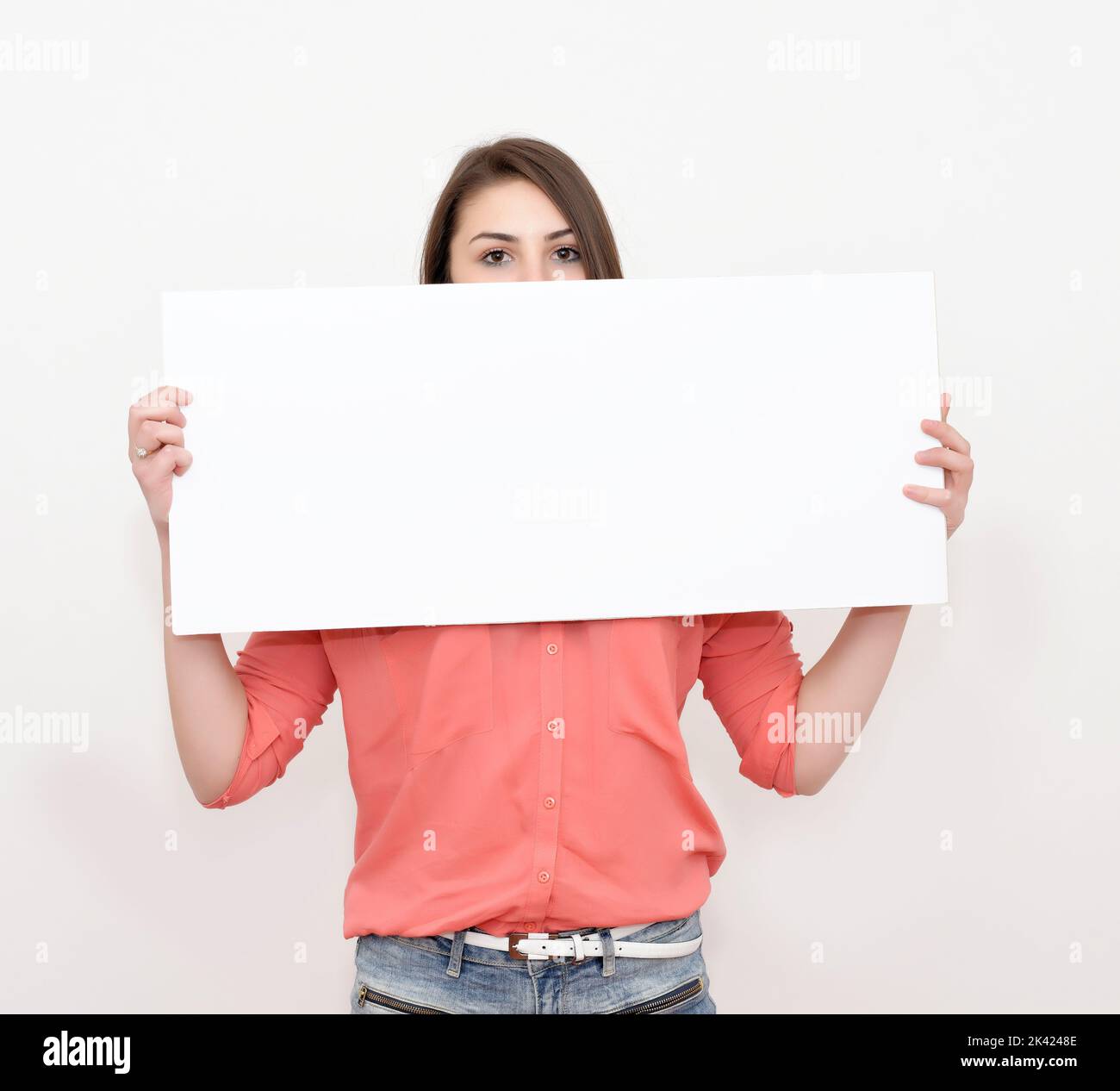 Young woman with an empty sheet of paper half covering face stock photo ...