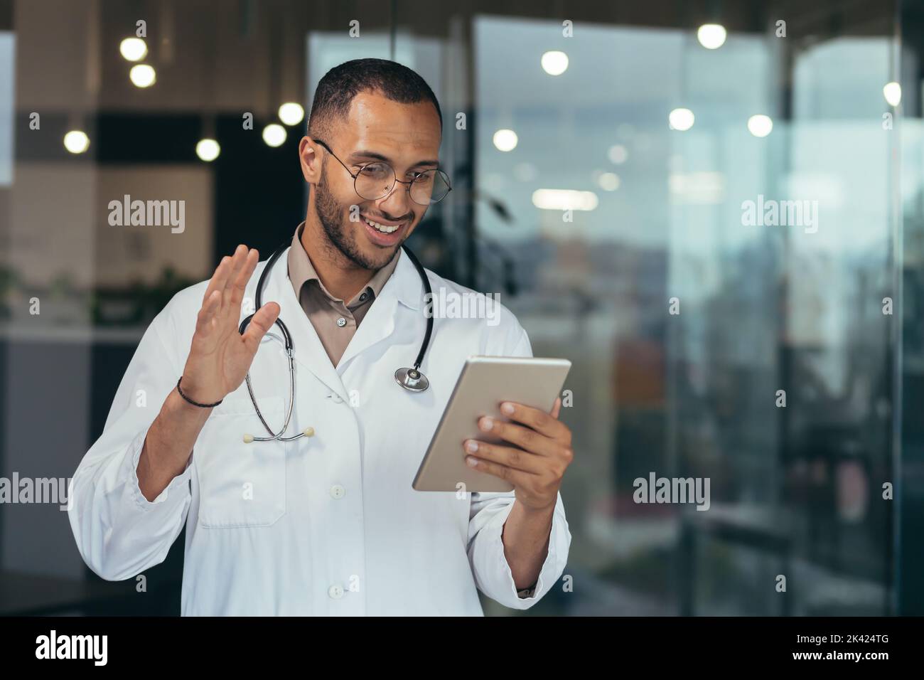 Cheerful hispanic doctor in medical white coat and stethoscope using ...