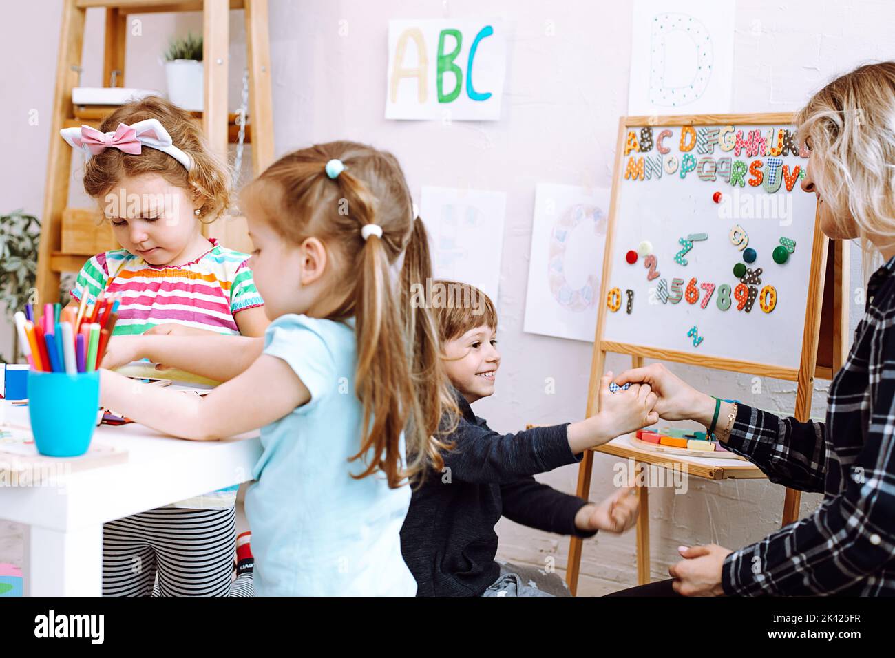 Female teacher with children have fun in development center. Paintings ...