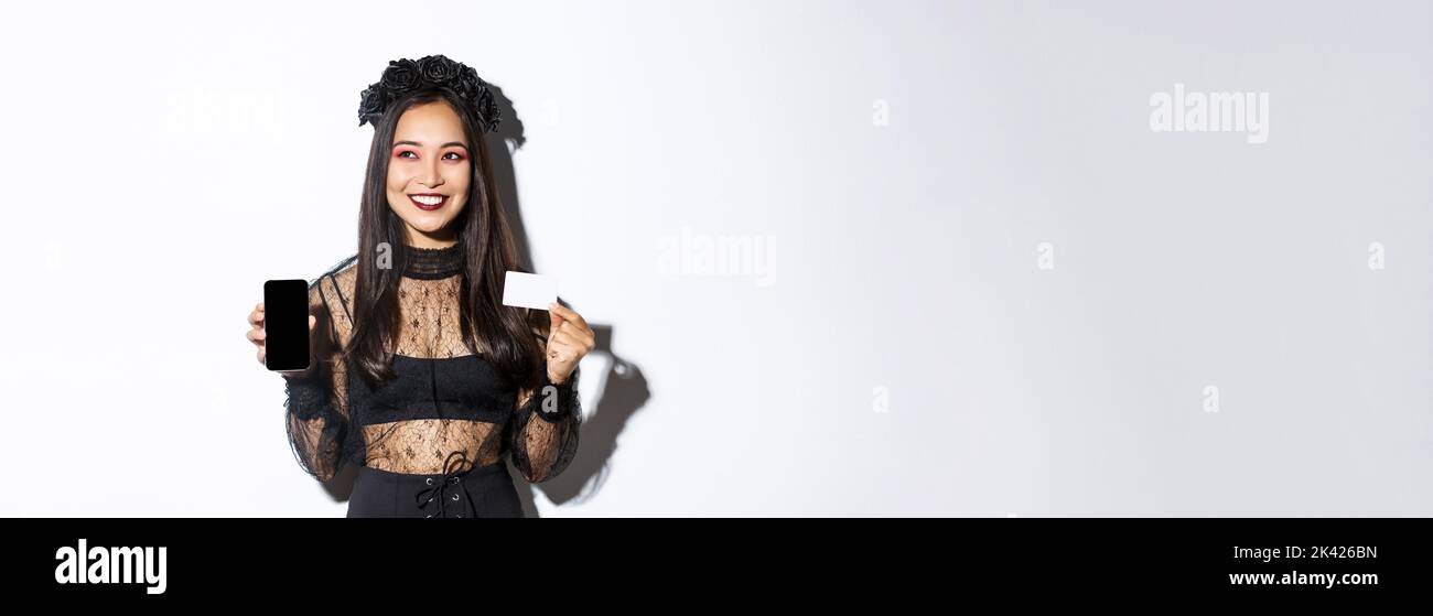 Dreamy smiling girl looking away while thinking, showing credit card ...