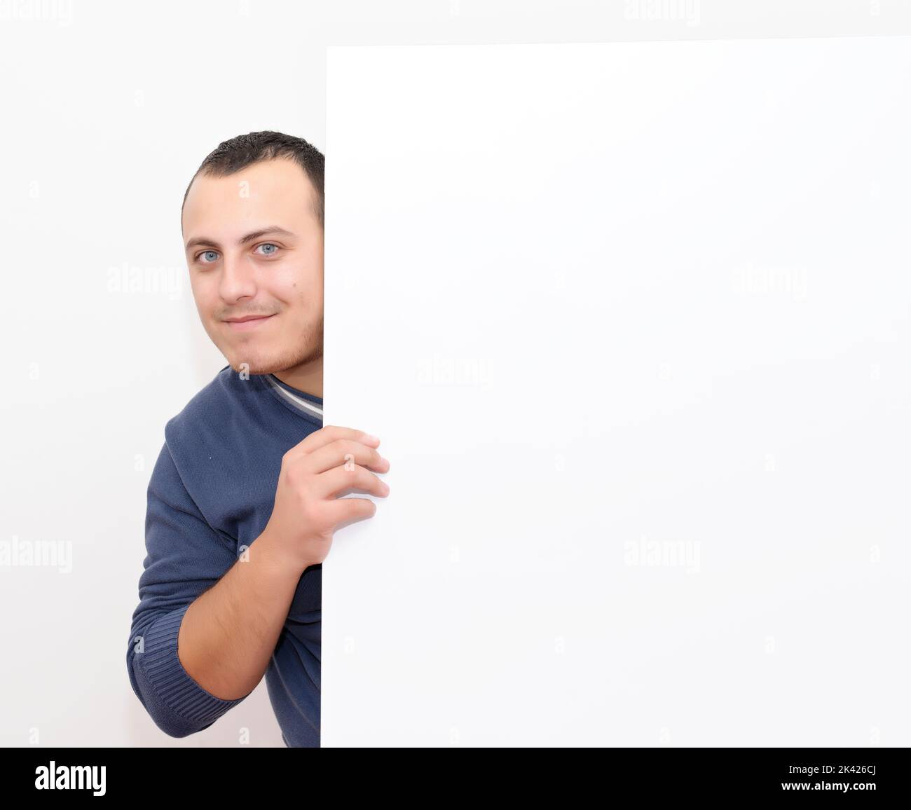 A smiling handsome male posing behind a white panel isolated stock ...
