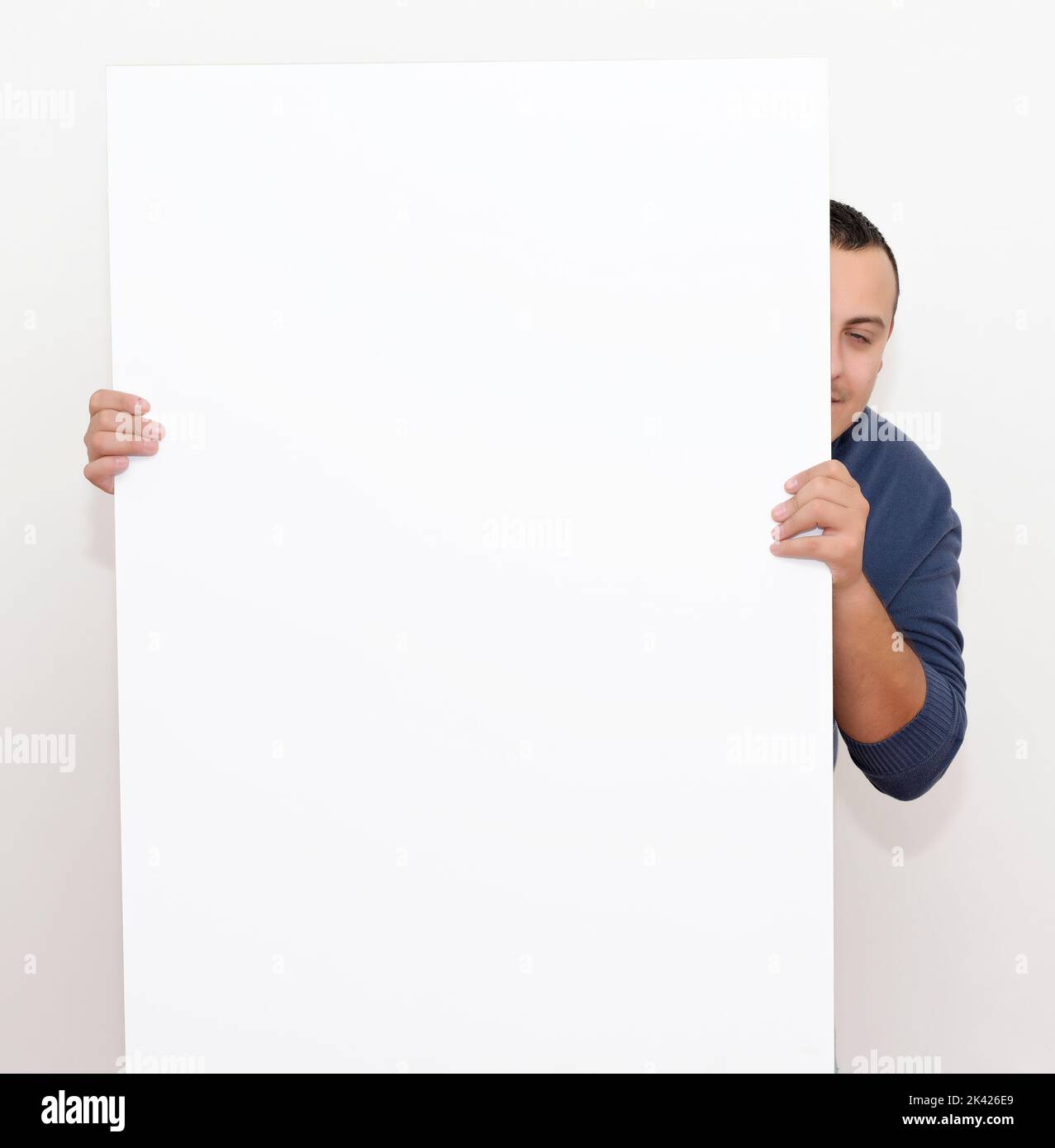 A smiling handsome male posing behind a white panel isolated stock ...