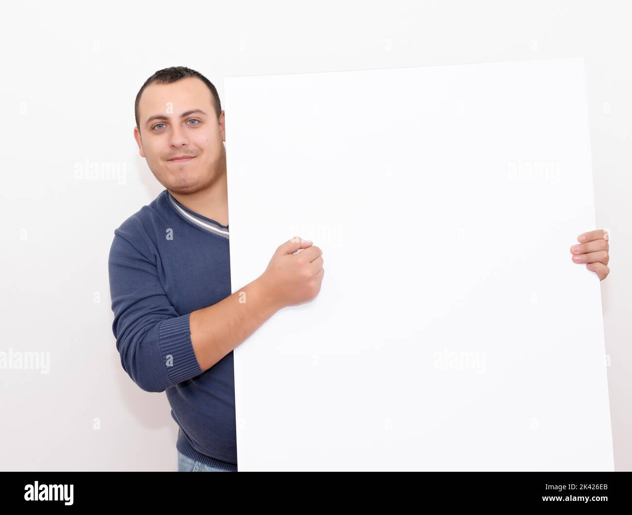 A smiling handsome male posing behind a white panel isolated stock ...