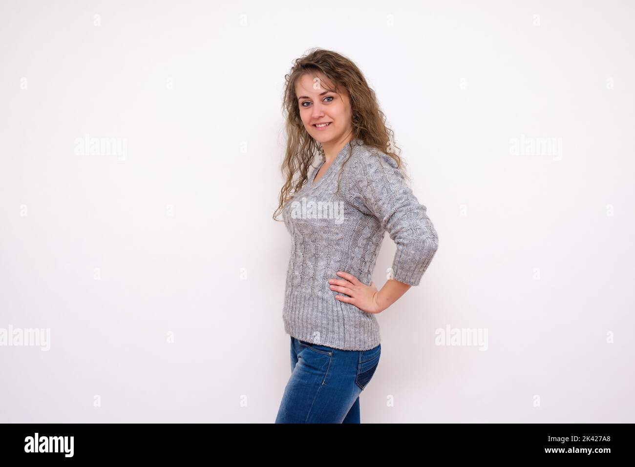 Smiling woman with her hand on her hip against a white background Stock ...