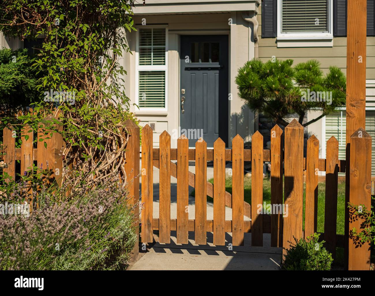 Entrance to a home through a beautiful green garden with flowers ...