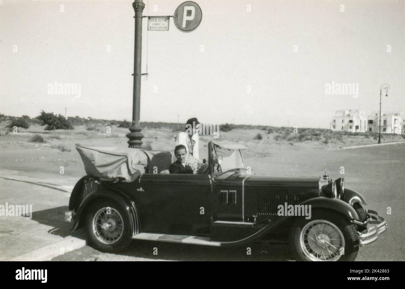 Couple with an old convertible car at the seaside in Ostia, Italy 1920s ...
