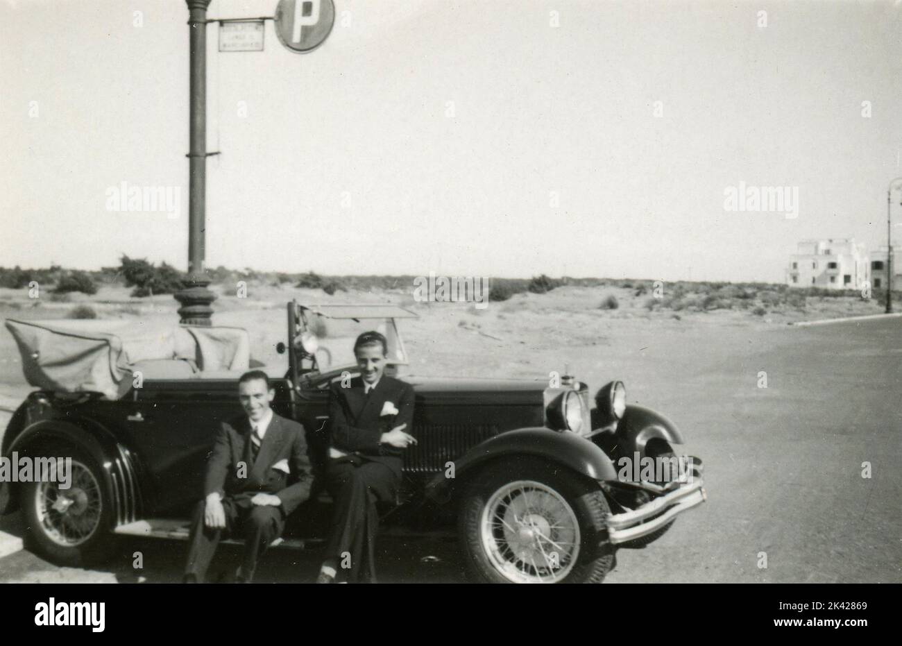 Two men with an old convertible car at the seaside in Ostia, Italy ...