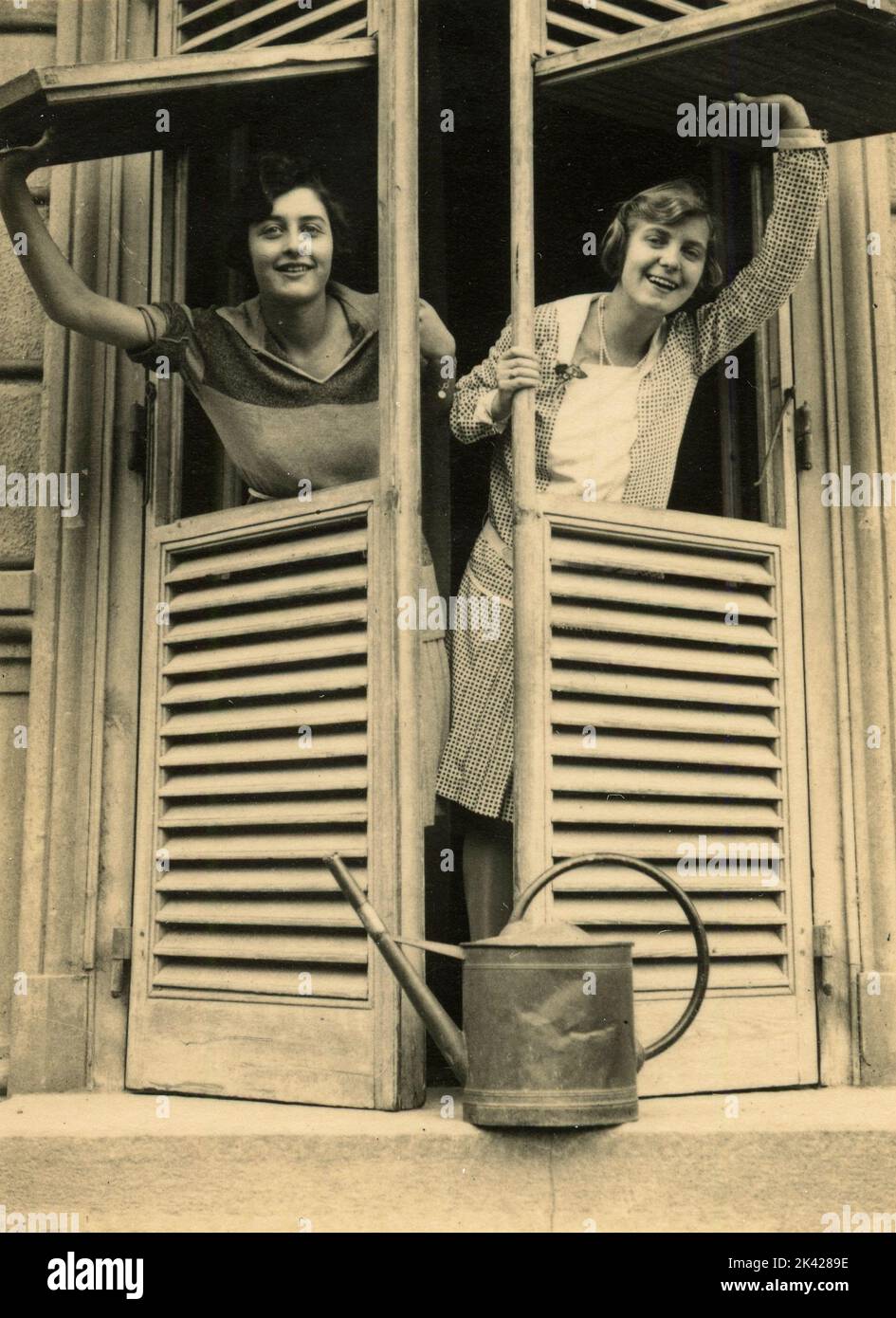 Two women looking out from the window shutters, Italy 1928 Stock Photo ...