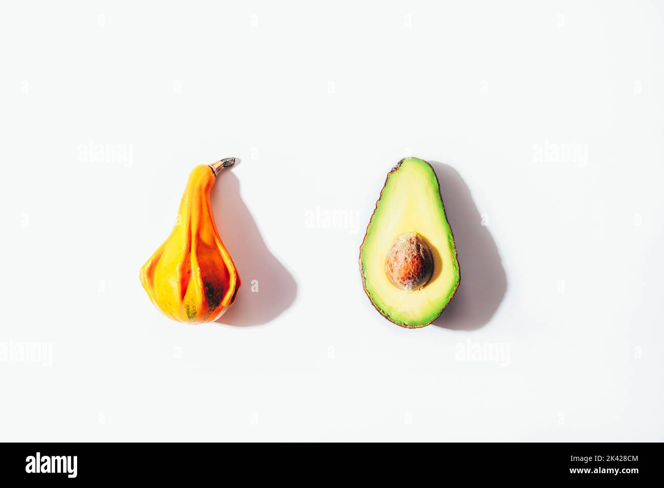 Pumpkin and avocado with harsh shadows on white background. Healthy ...
