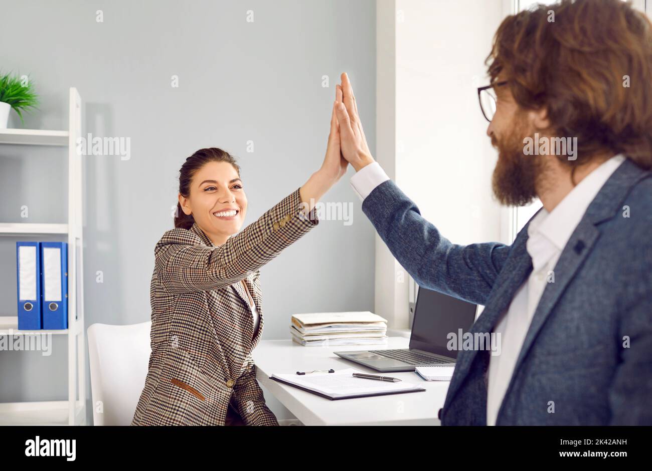 Joyful positive colleagues in office give each other high five after ...