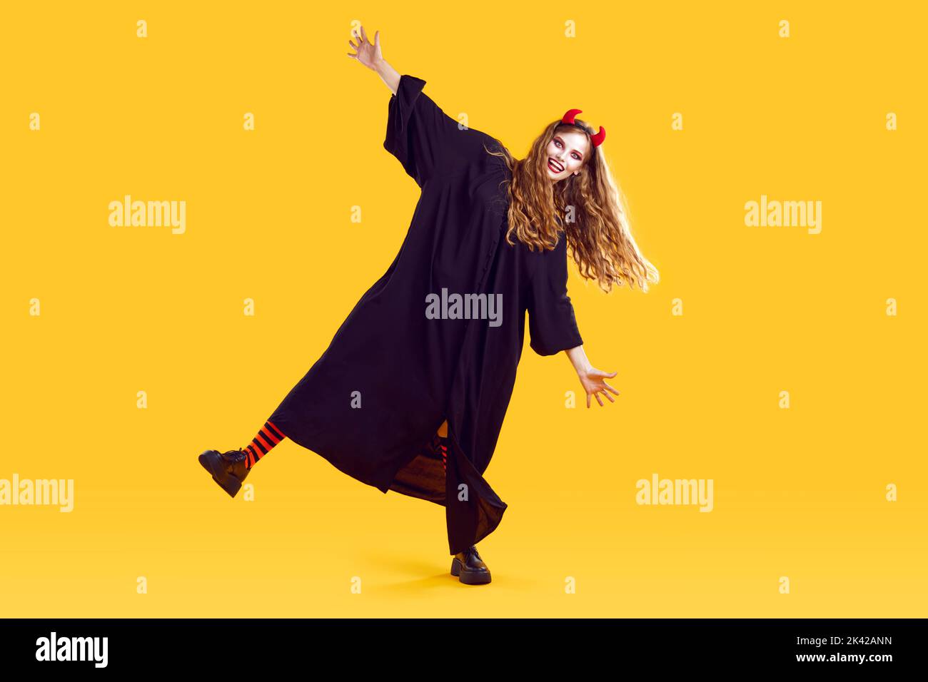 Funky woman in halloween costume, terrifying makeup, red devil horns ...