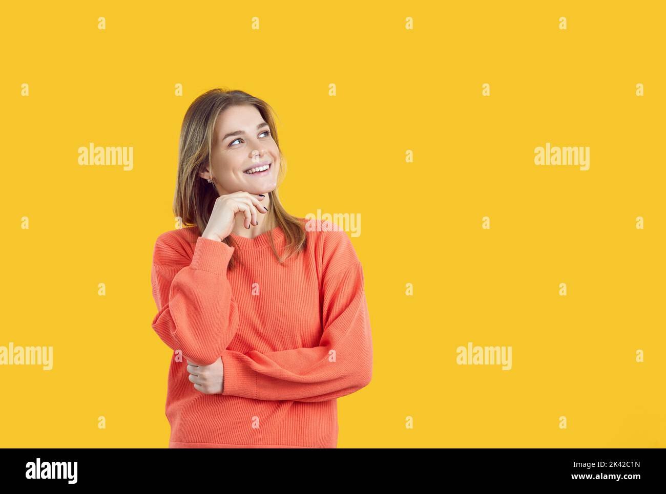 Happy young girl thinking or dreaming of something good on yellow copy ...