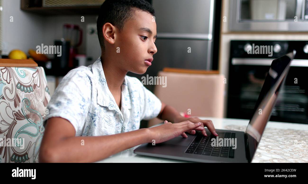 Black kid in front of laptop at home. Child browsing internet online ...