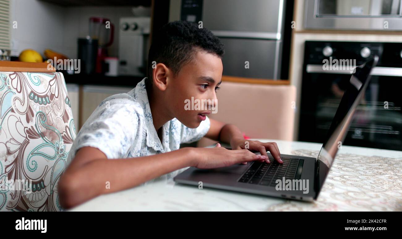 Black kid in front of laptop at home. Child browsing internet online ...