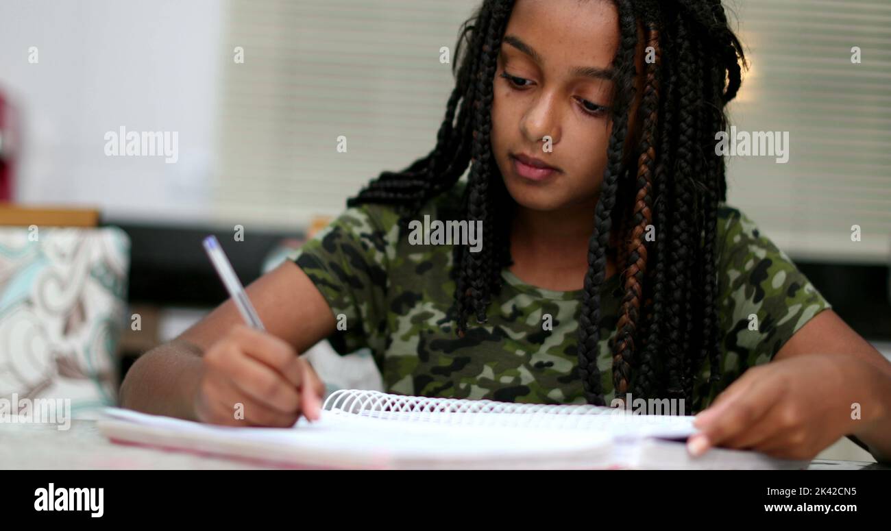Black teen girl doing homework at home writing paper studying Stock ...
