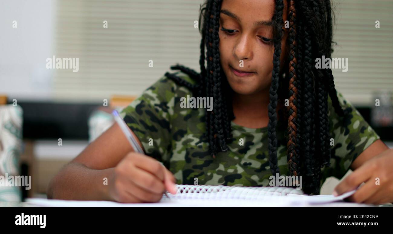 Black teen girl doing homework at home writing paper studying Stock ...