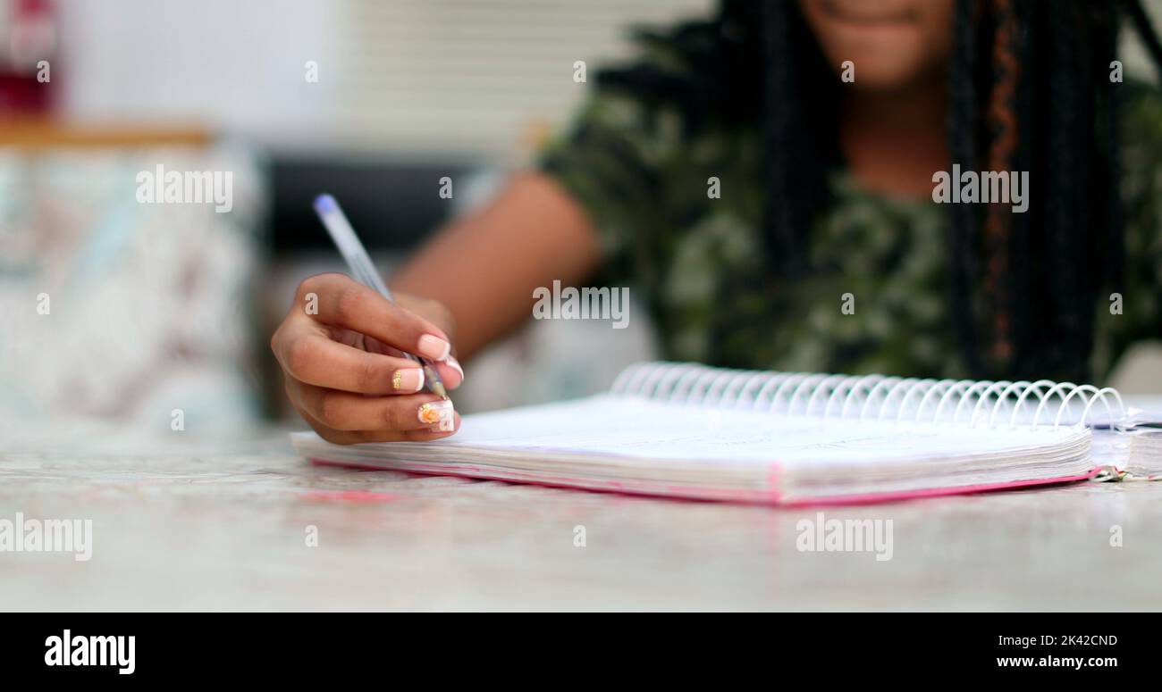 Black teen girl doing homework at home writing paper studying Stock ...
