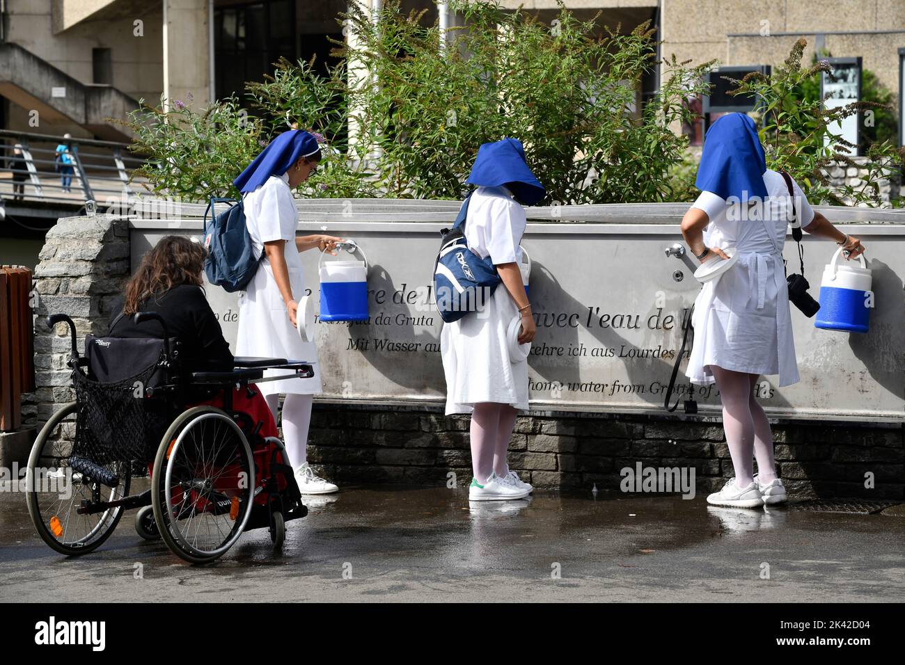 Lourdes, Hautes-Pyrénées, France. Christian pilgrims collecting Lourdes ...