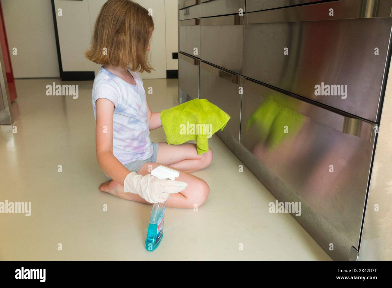 Young girl aged eight years old cleaning and polishing the kitchen with ...