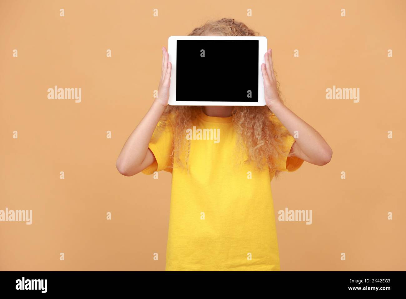 Amazed kid in hiding behind digital tablet with empty screen over ...