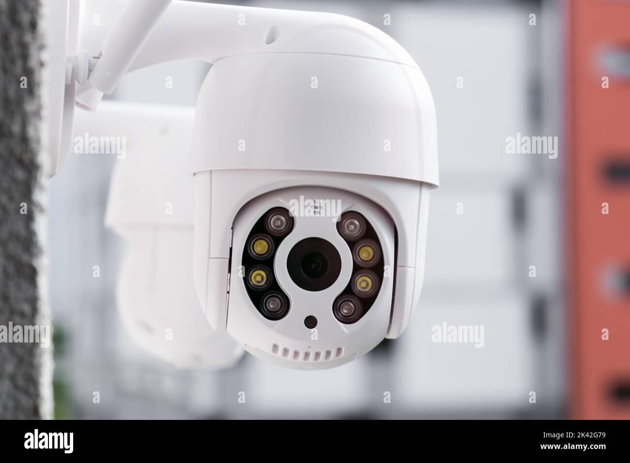 Modern CCTV camera on a wall with a blurred multi-storey building on ...