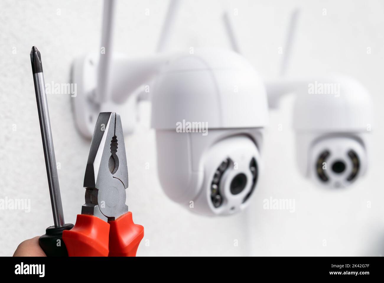 Technician installing CCTV camera using pliers and screwdriver outside ...