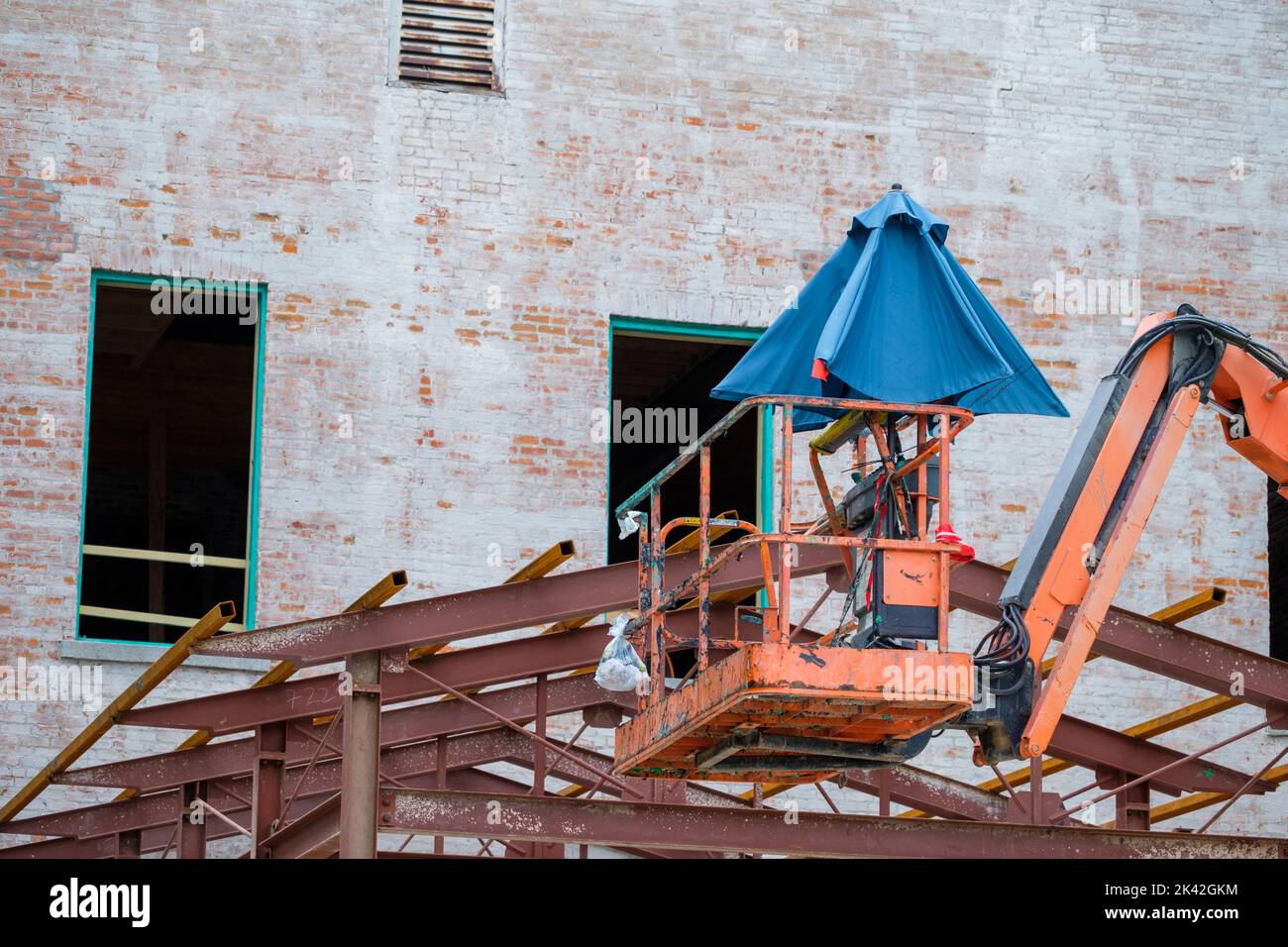 Empty cherry picker lift with folded umbrella at construction site in ...