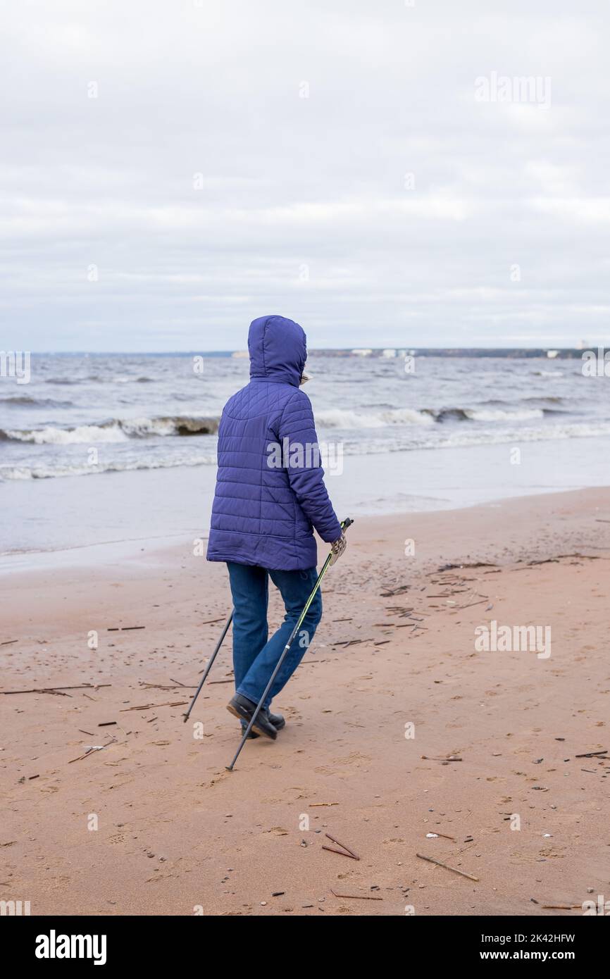 Senior retired woman hiking on the seaside on the sand. Active, fitness ...