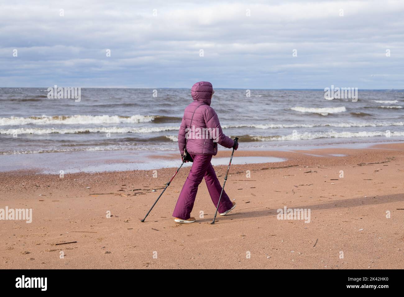 Senior retired woman hiking on the seaside on the sand. Active, fitness ...