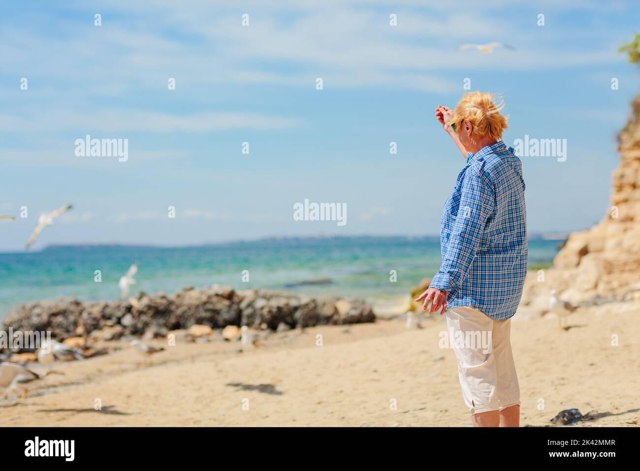Elderly woman standing on the beach and looking into the distance Stock ...