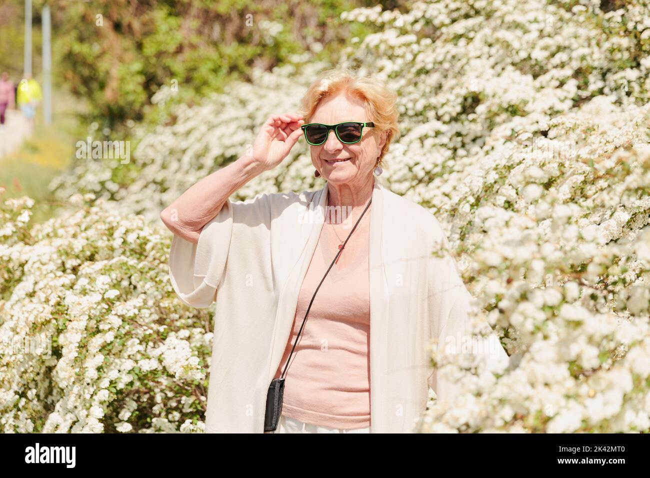 Elderly woman posing among bushes with white flowers Stock Photo - Alamy