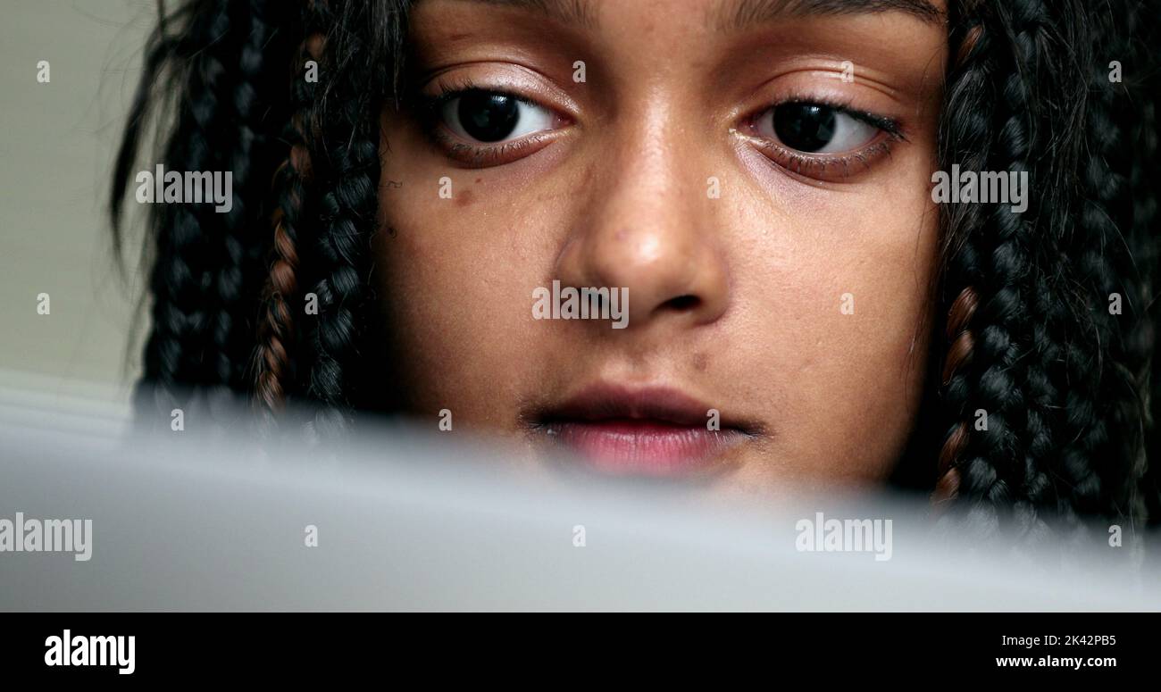 Close-up girl face looking at computer screen. Child staring at laptop ...