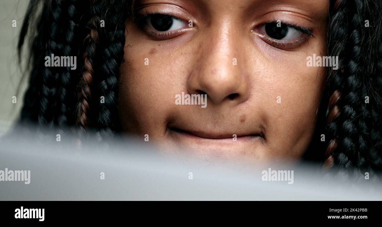 Close-up girl face looking at computer screen. Child staring at laptop ...