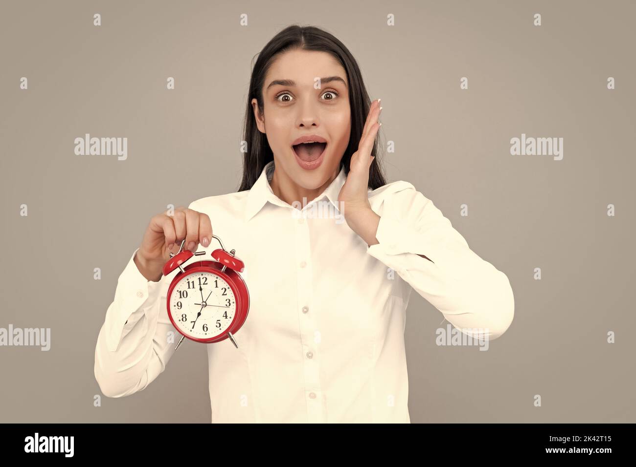 Woman holds a clock. Emotional young female face. Portrait of young ...