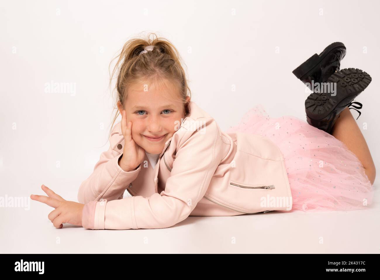 Portrait of attractive cheerful girl lying on floor enjoying pastime ...