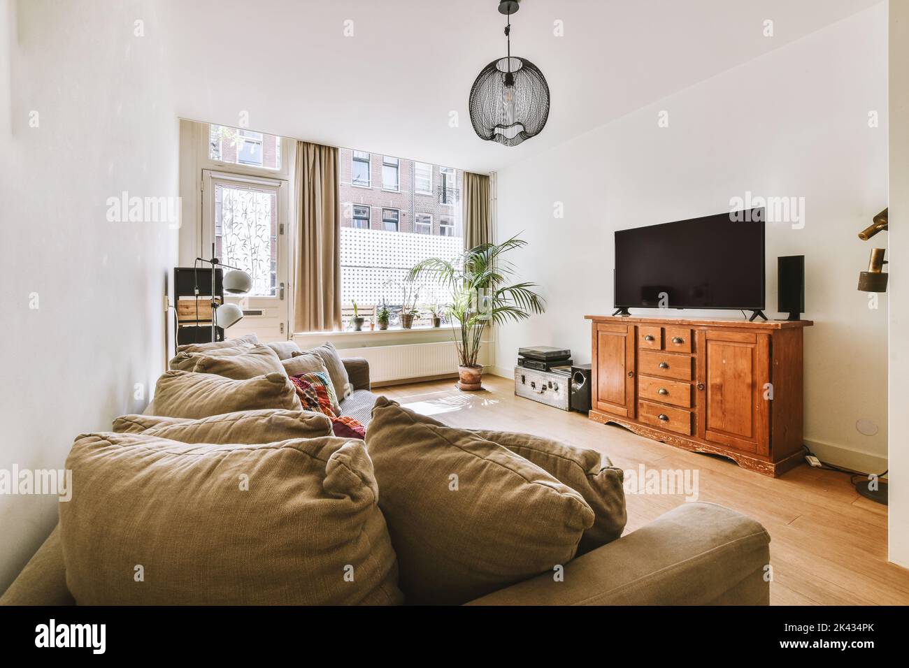 Interior of living room with comfortable sofa and TV against windows in ...