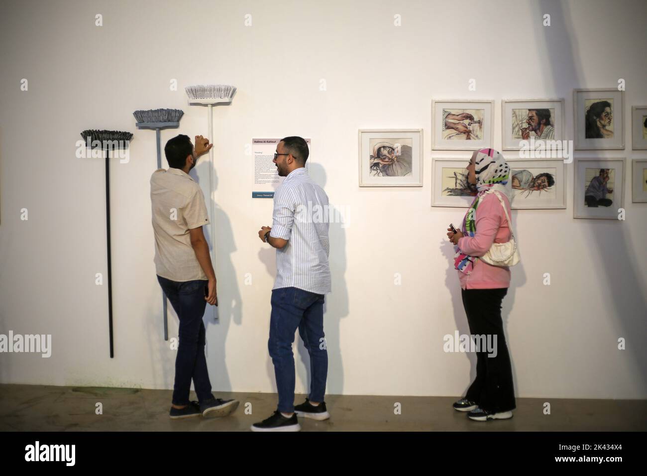 Palestinians look at the artworks during a contemporary art exhibition ...