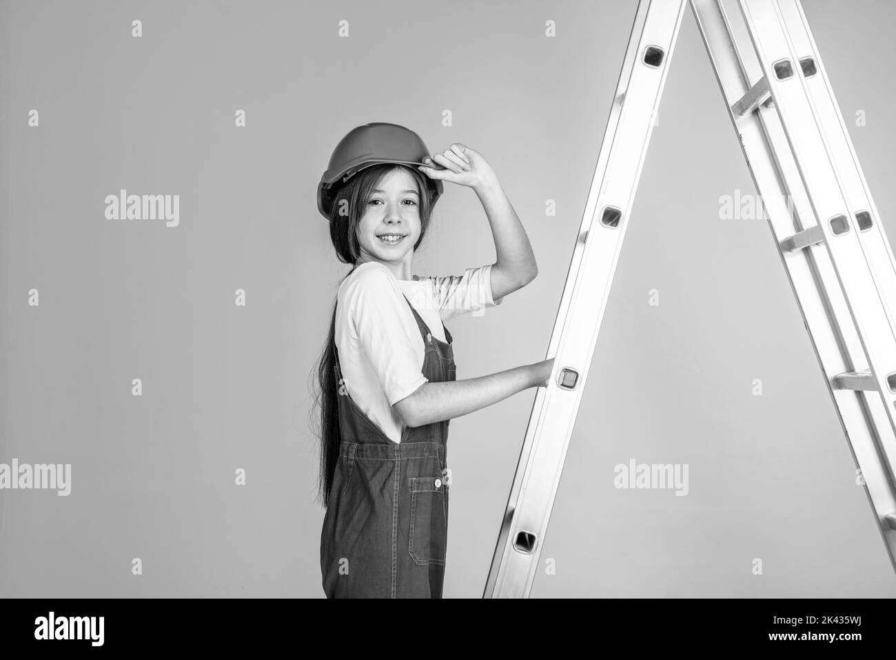 teen girl in uniform and helmet with ladder. female builder in hard hat ...