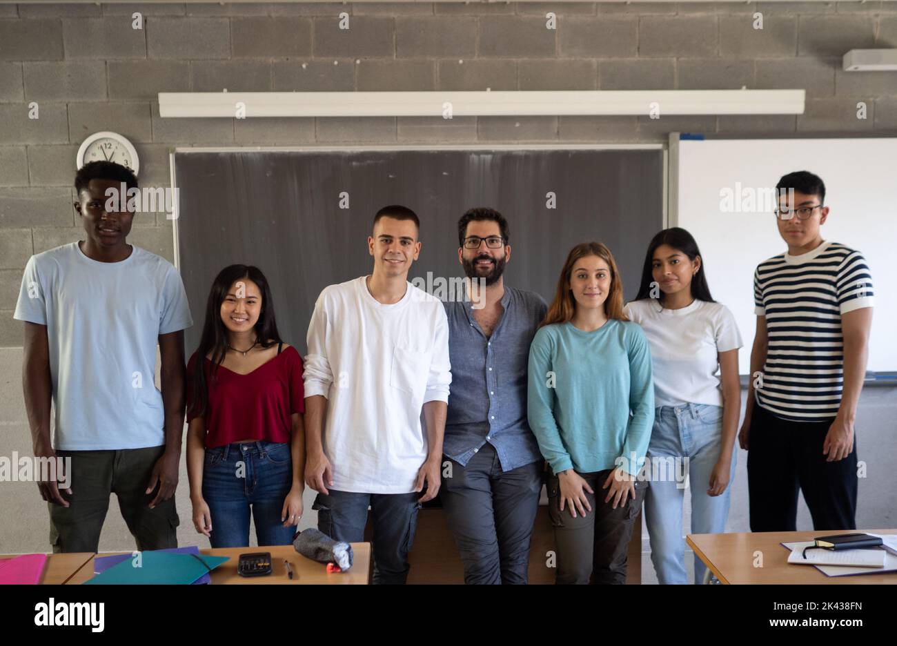 Group of diverse teenage students and a male teacher smiling looking at ...