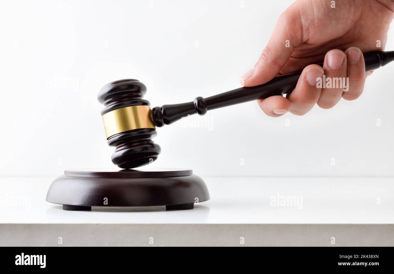 Hand striking on wooden base with judge's mallet on white table and ...