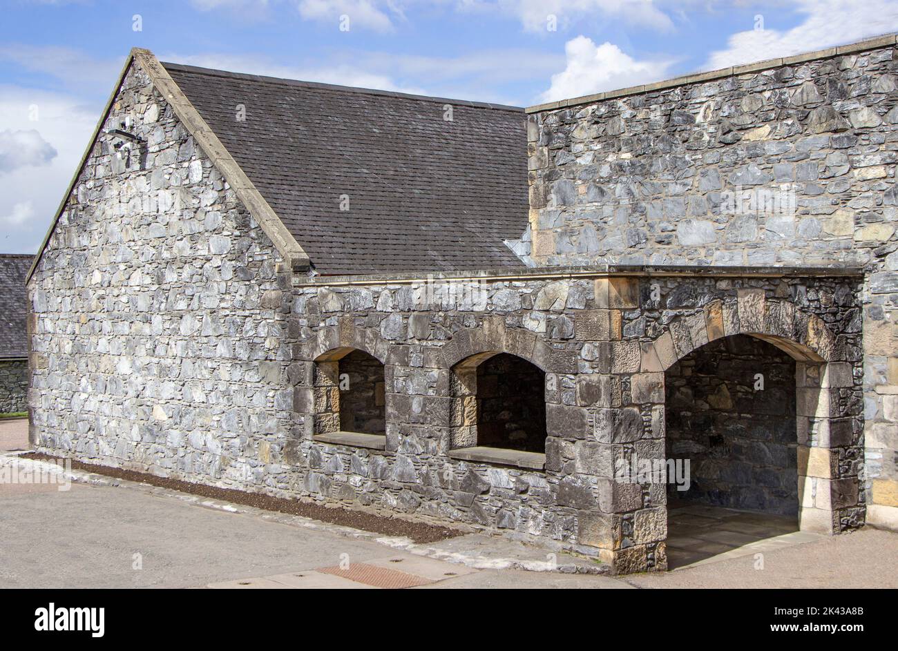Old stone built building wih slate roof, open windows and an arched ...