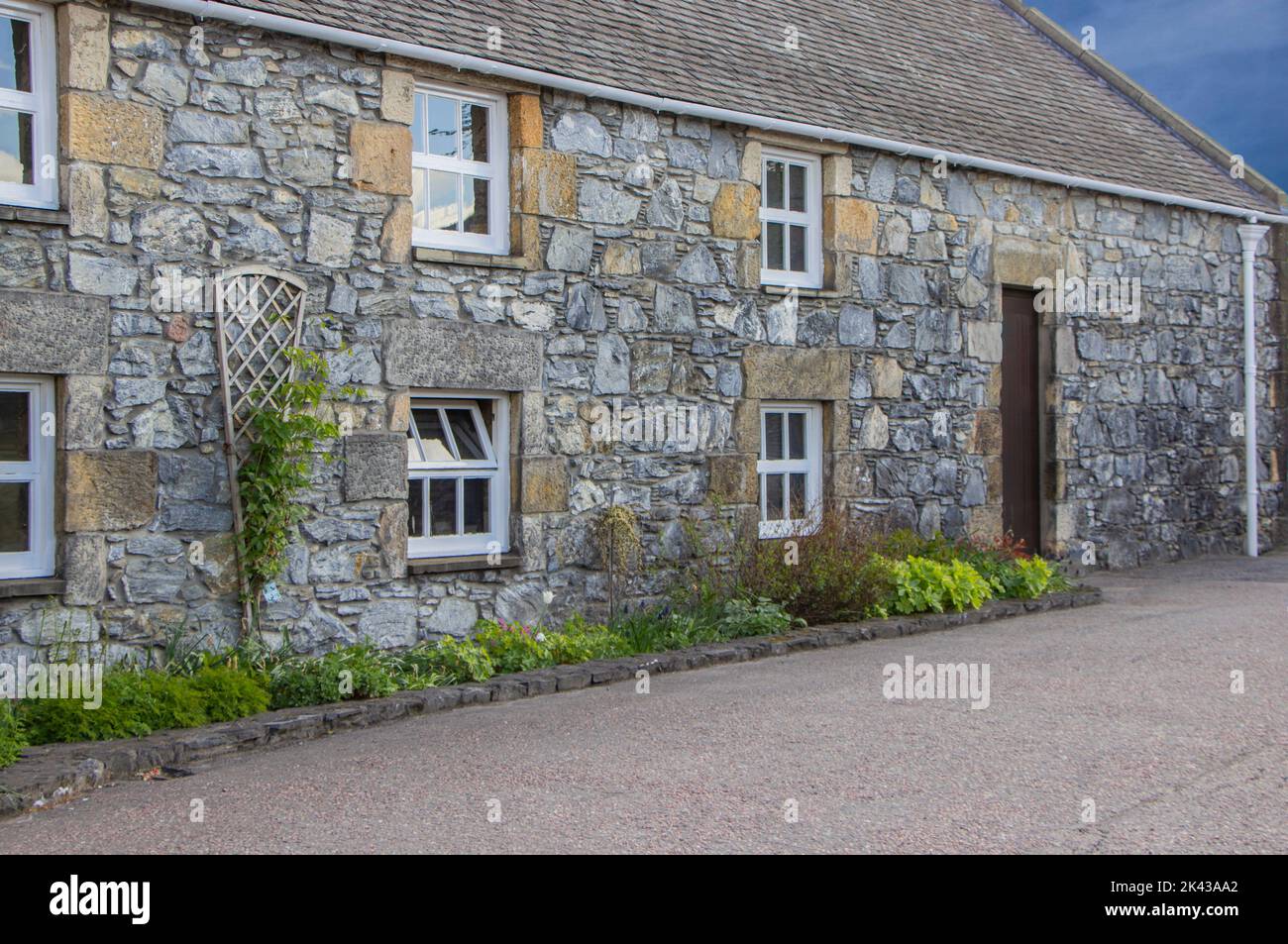 Looking long a pathway at a Stone built building with a door and a ...